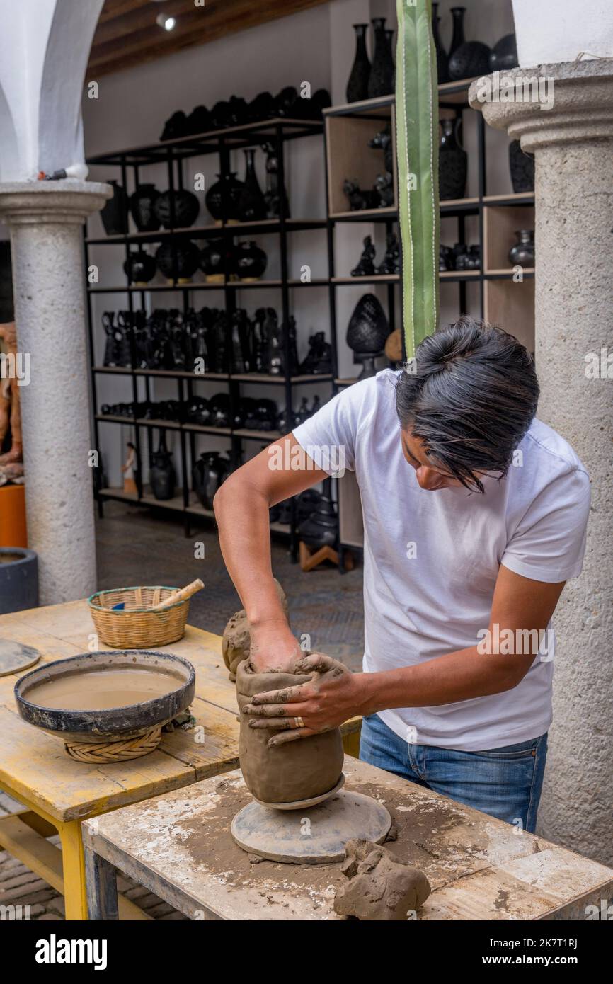 A potter is making a Barro negro pottery (black clay pottery) vase ...