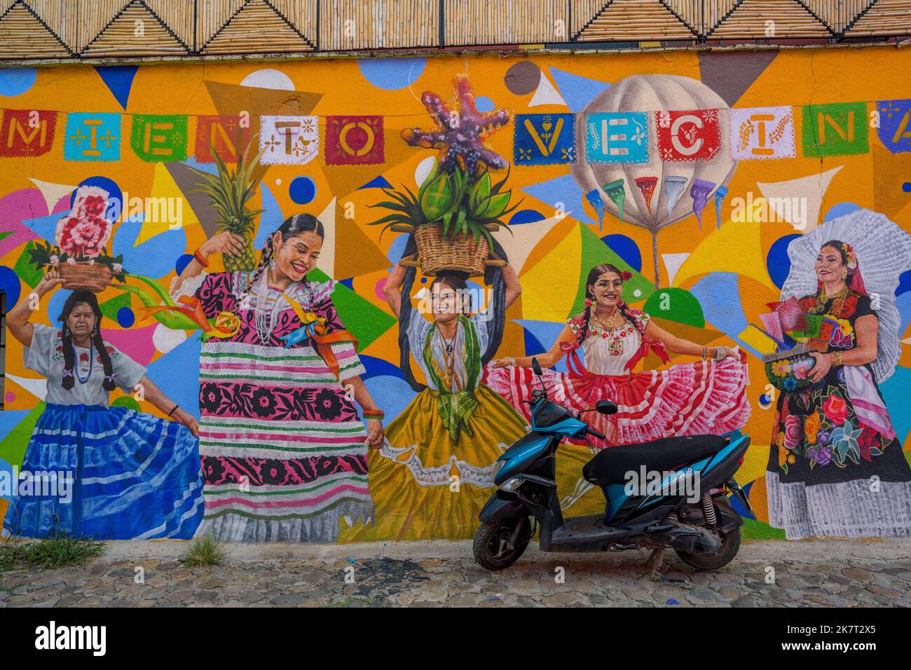 A motor scooter parked in front of a colorful mural in a street of ...