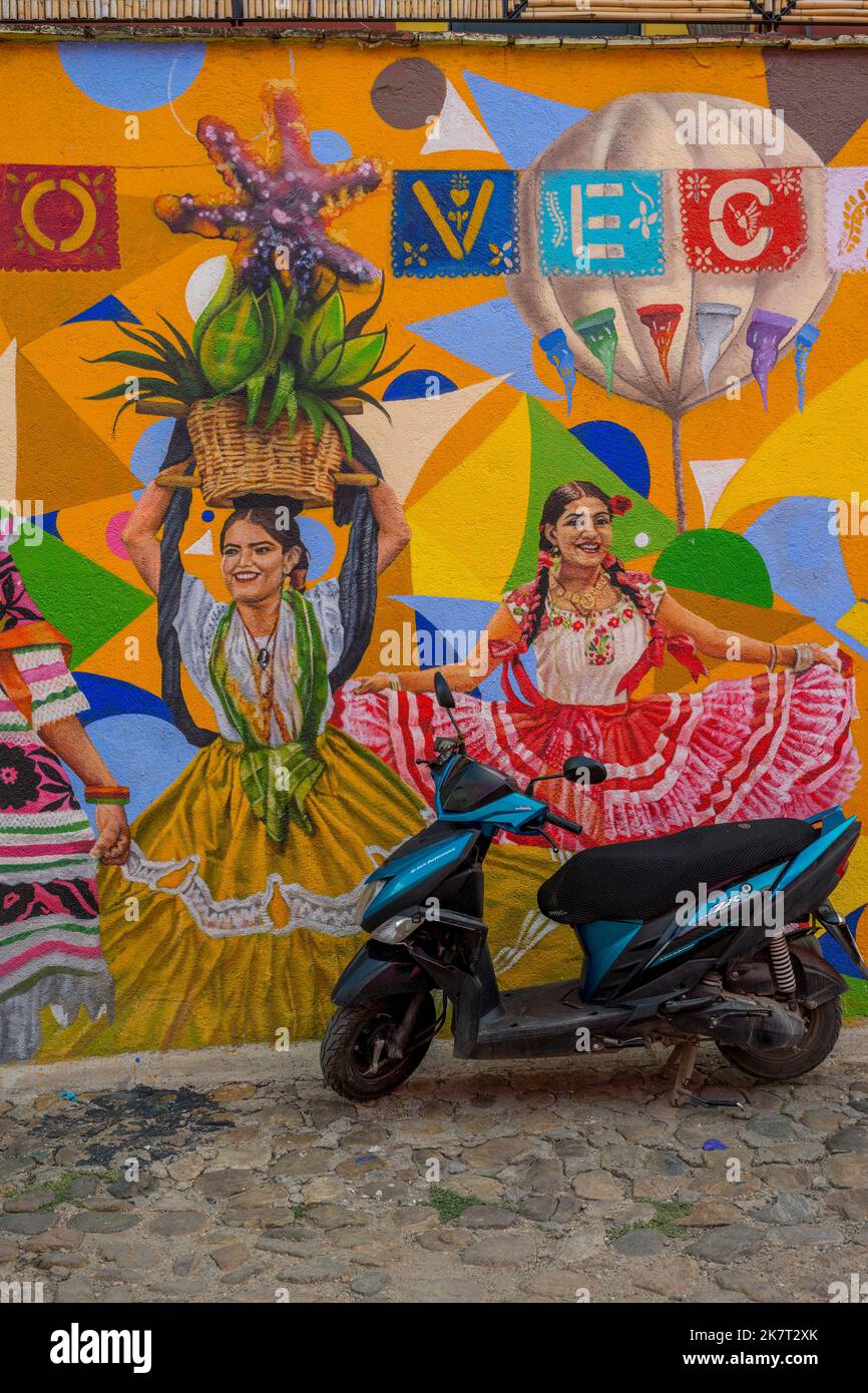 A motor scooter parked in front of a colorful mural in a street of ...