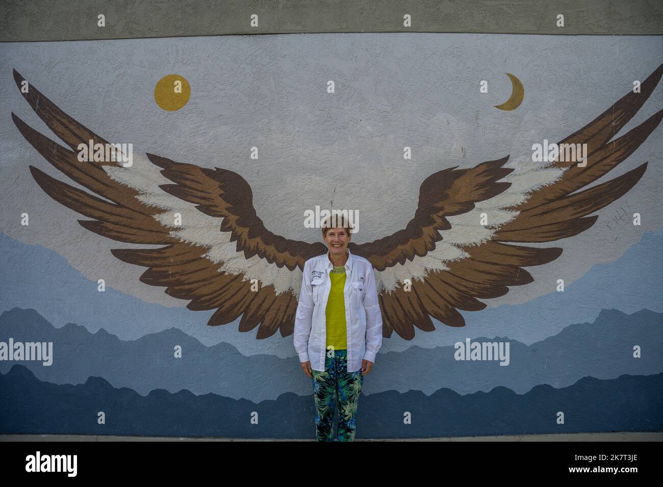 A woman (Model Released) is posing in front of painted wings on a wall ...