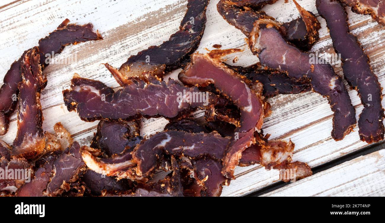Sliced traditional South African biltong or cured meat on rustic white ...