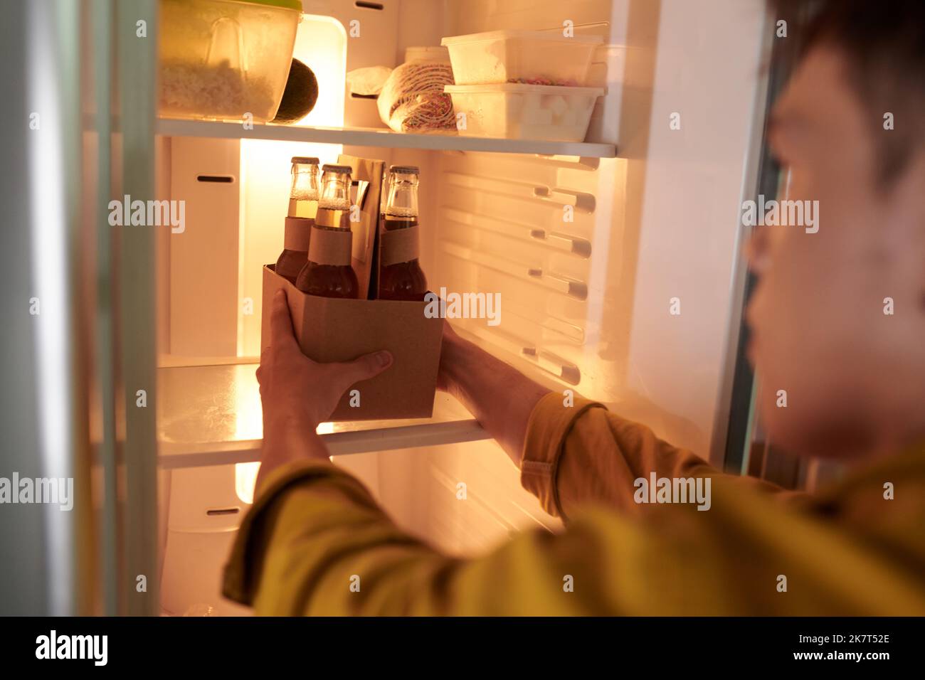 Young man putting beer pack in refrigerator to keep it cold for party ...