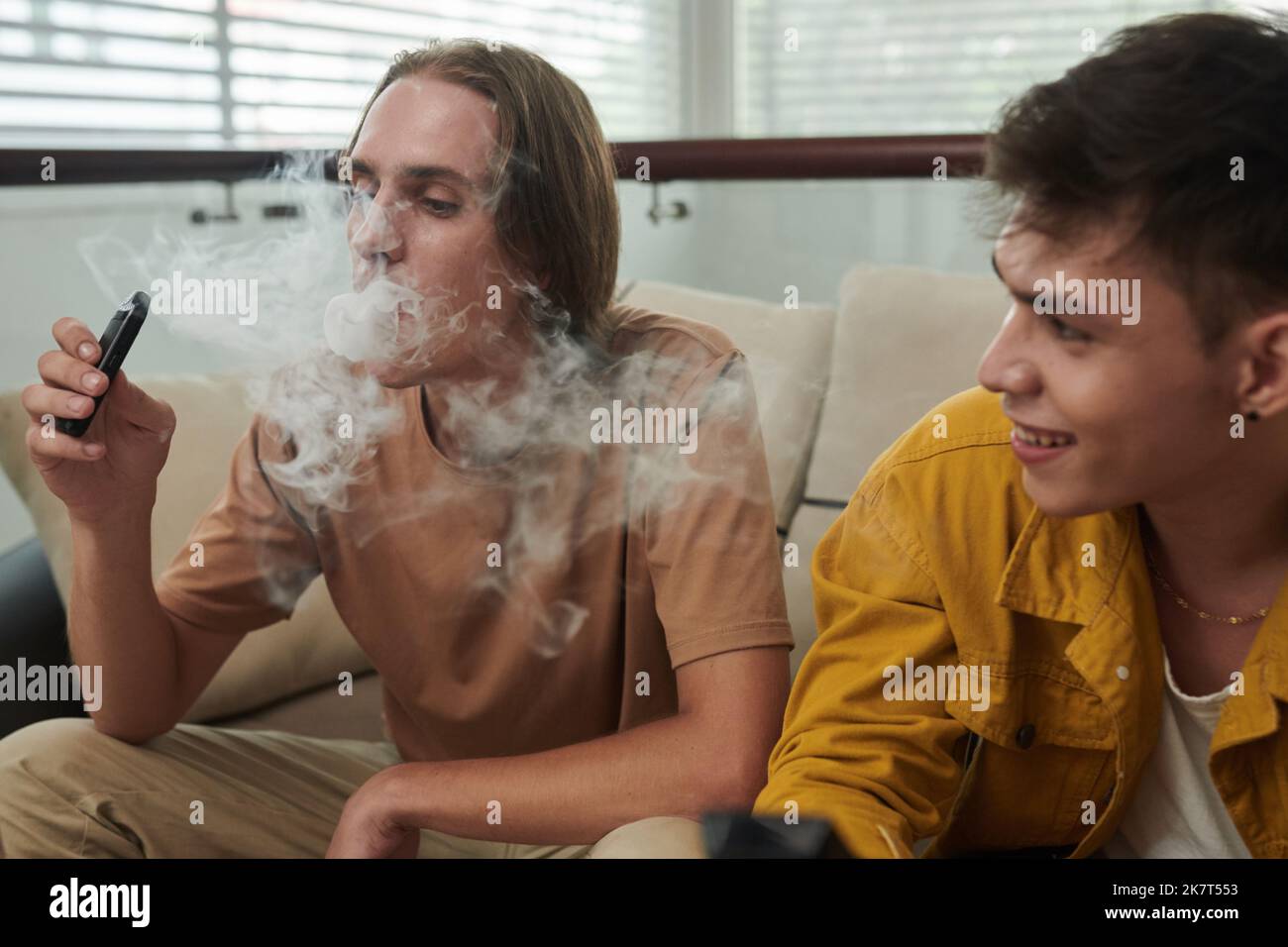 Young man smoking vape when spending time with best friend Stock Photo ...