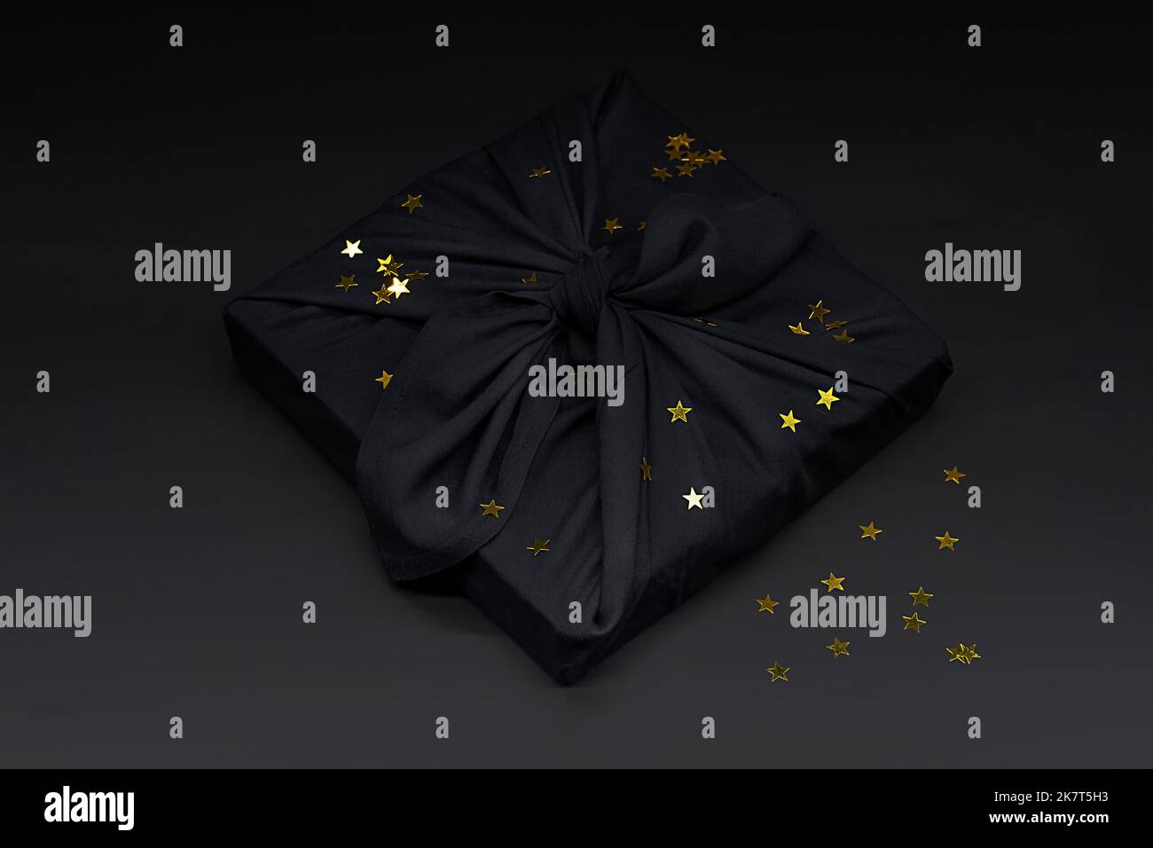 Black friday gift box wrapped in fabric with golden confetti ...