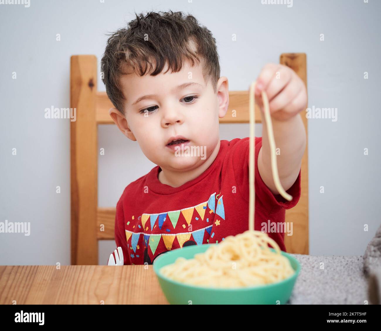 Cute boy is playing with his pasta at lunch time Stock Photo - Alamy