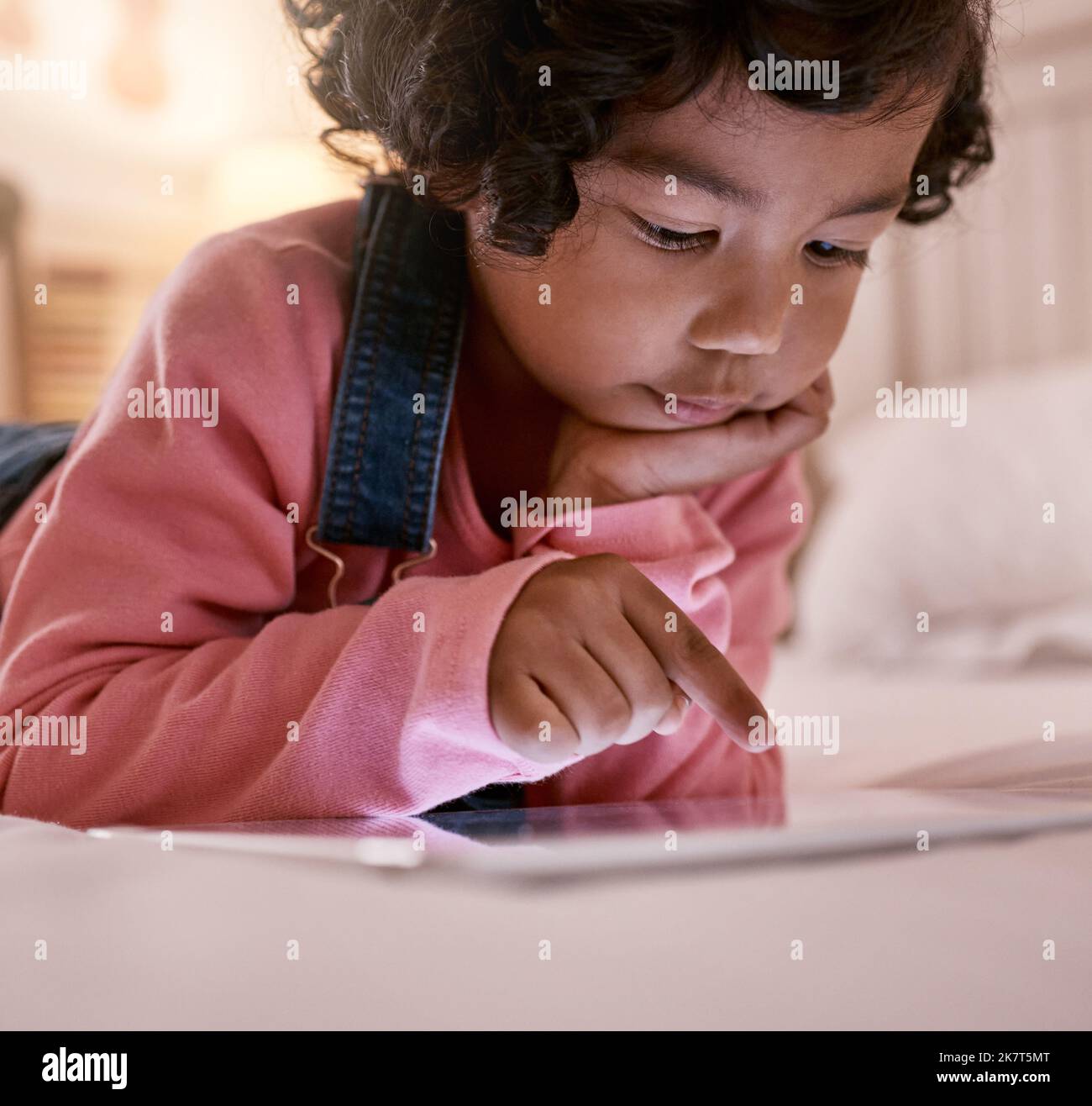 Learning through technology. a little girl using a digital tablet at ...