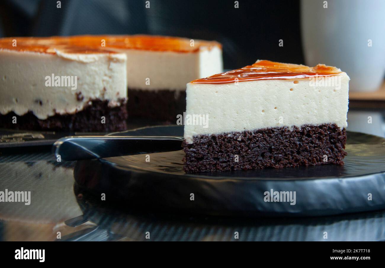 A piece of cheesecake with caramel on a plate with knife in the ...