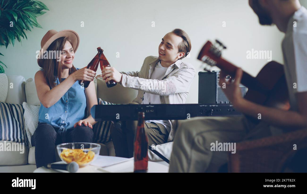 Cheerful young friends are having fun talking, singing and drinking ...