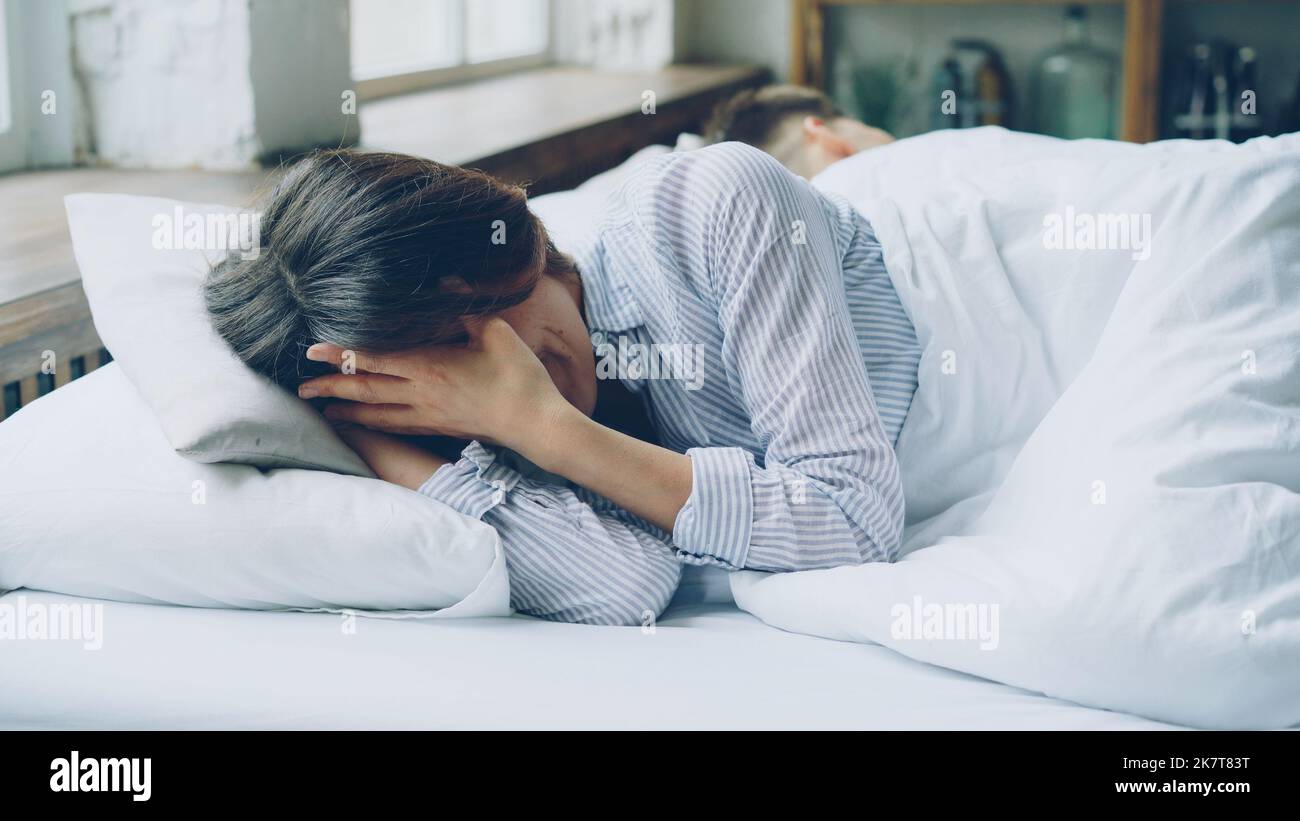 Sad woman is pajamas is lying in bed and crying after fight with her ...
