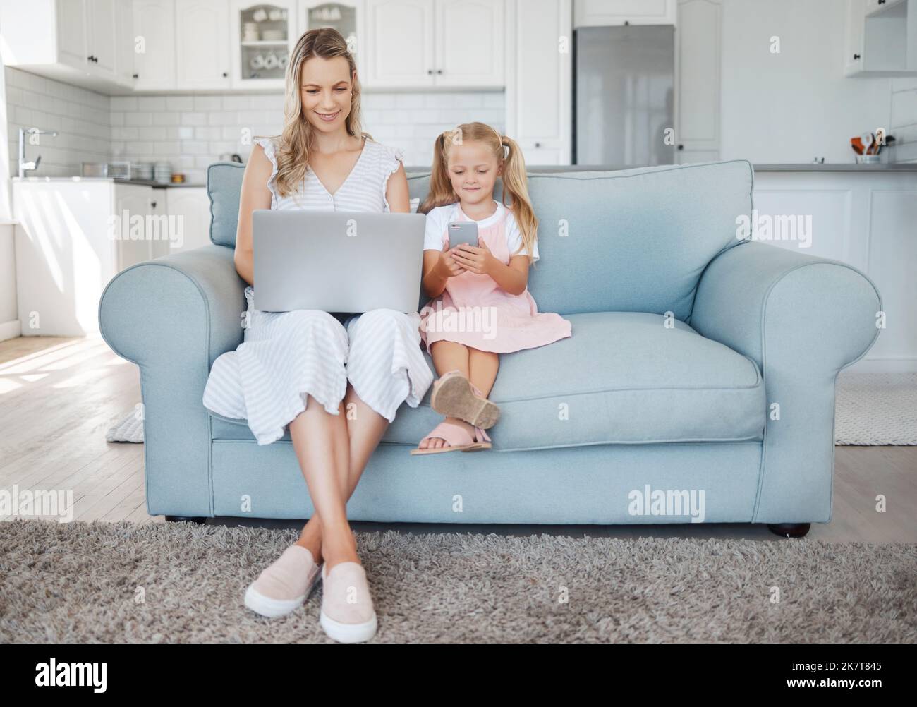 Family, phone and laptop with a girl and mother on the sofa in a home ...