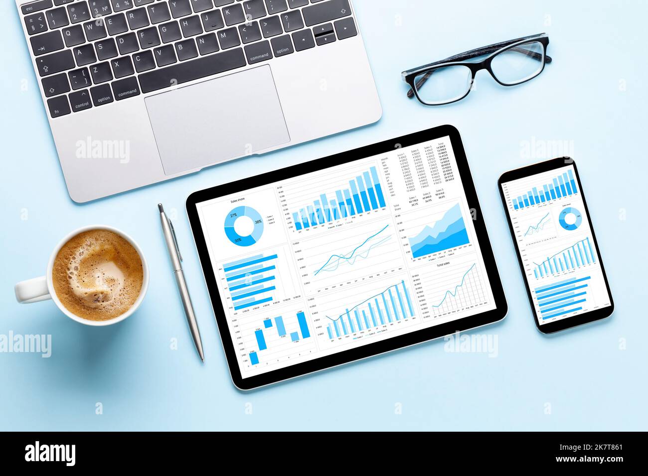 Tablet and smartphone with charts and reports on desk. Top view flat ...