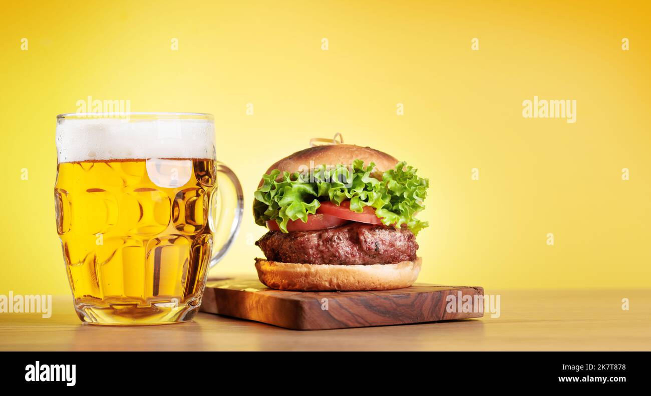 Beer glass and hamburger over color background Stock Photo - Alamy