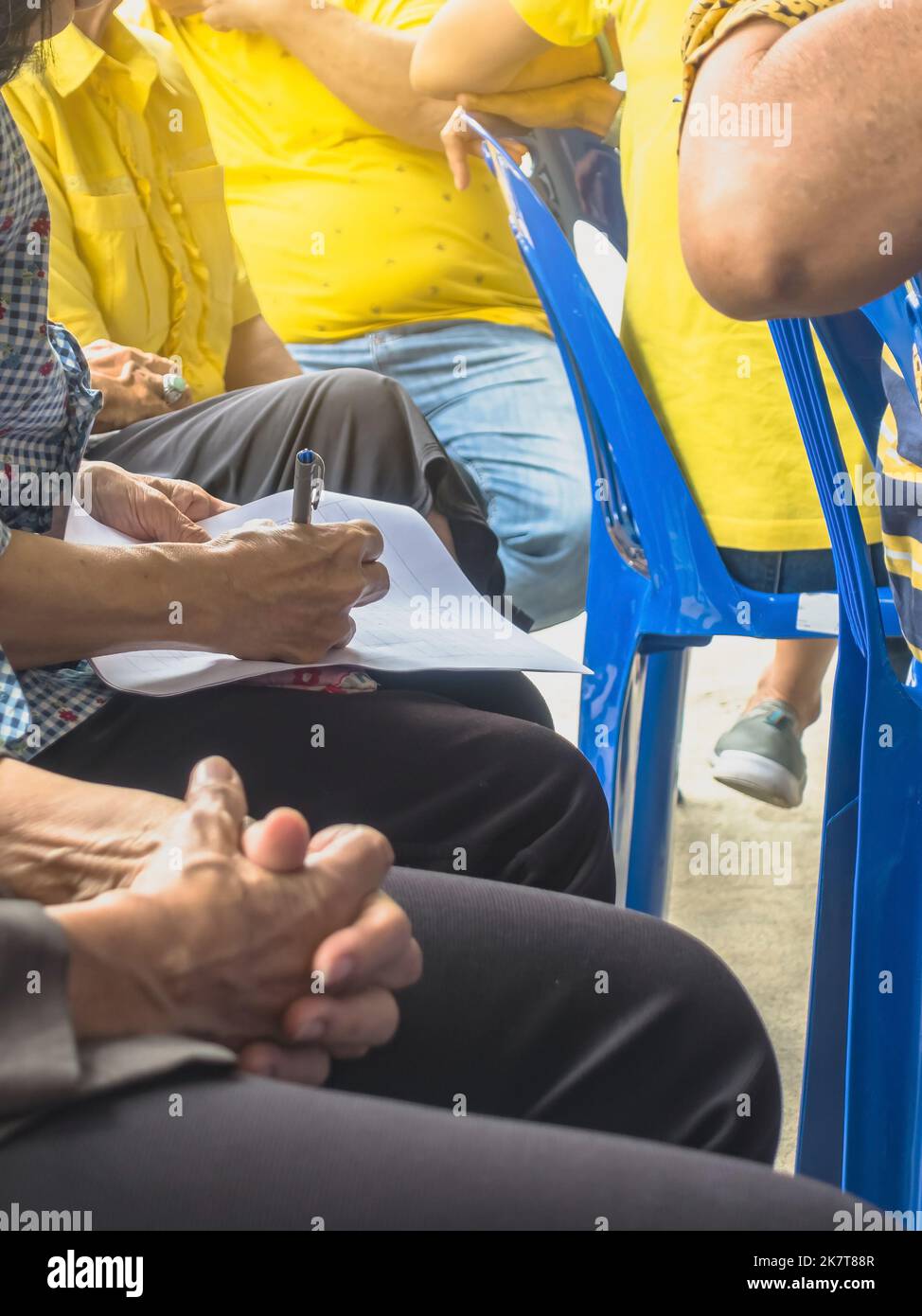 Hand of elderly woman holds a pen to prepare to take notes of local ...