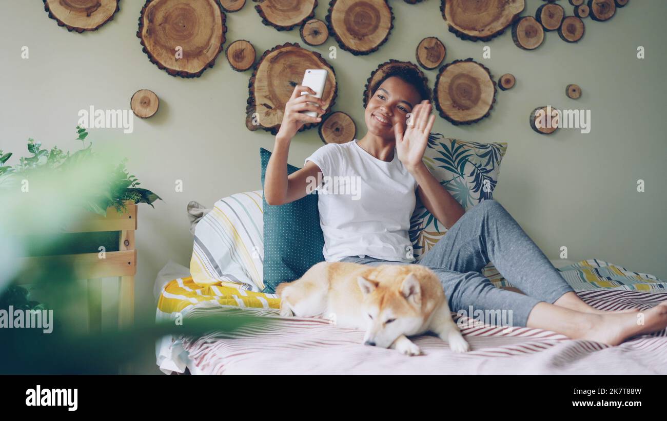 Happy African American teenager is making video call with smartphone ...