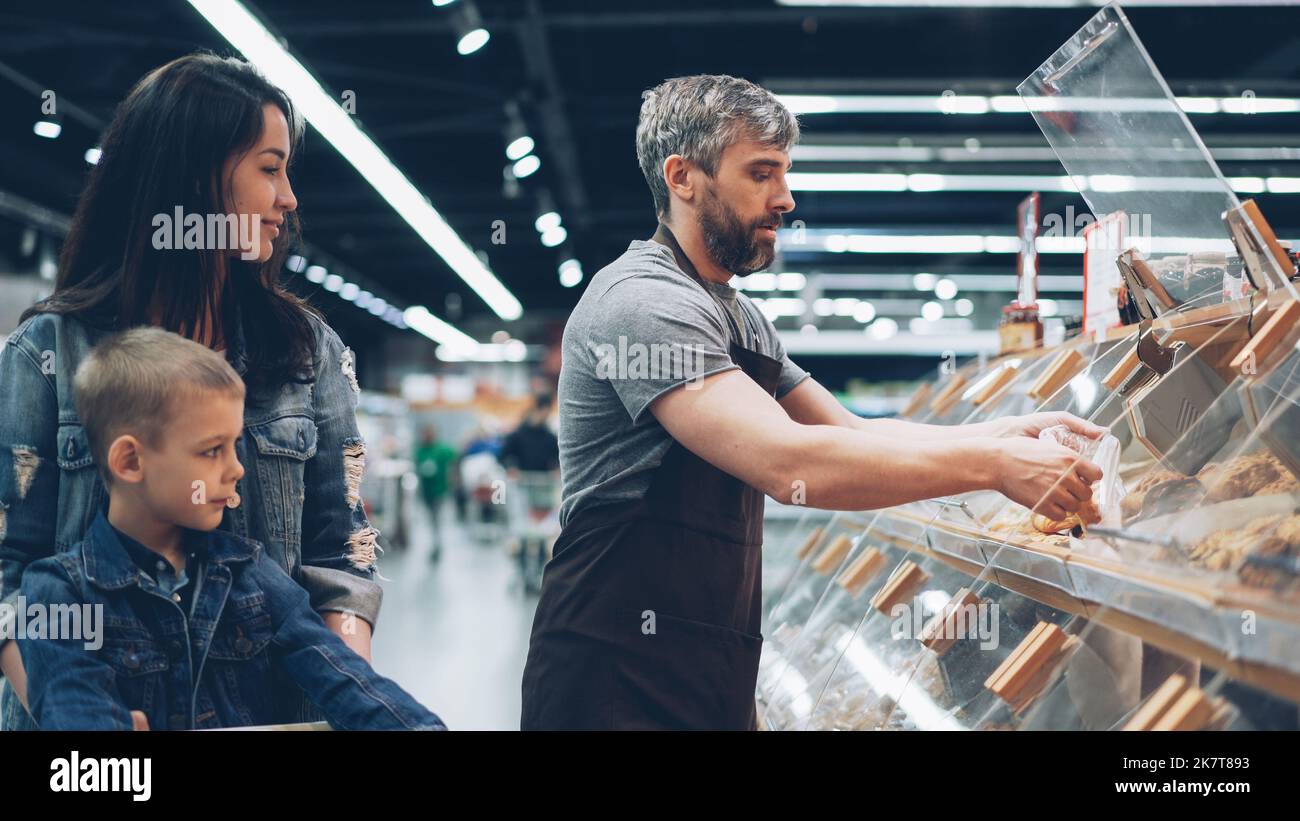 Male shop assistant is working in bakery department in supermarket then ...