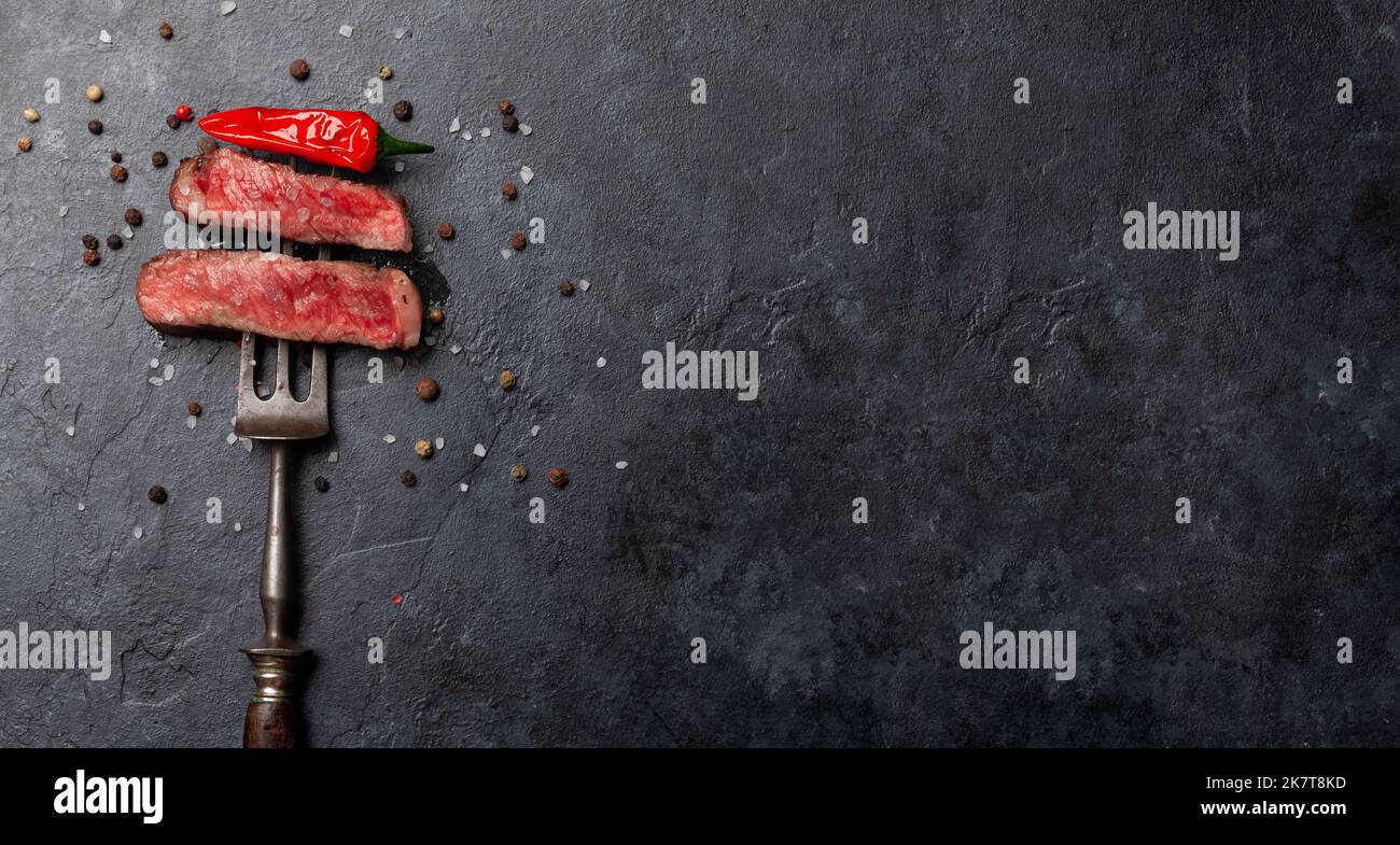 Grilled ribeye beef steak slices with herbs and spices. Flat lay with ...