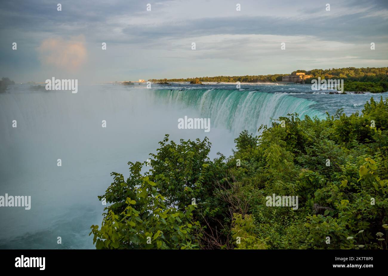 Niagara Horseshoe falls on sunset - blue water, haze and cloudy sky ...
