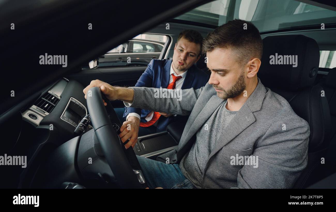 Bearded guy is discussing car features with smiling salesman sitting ...