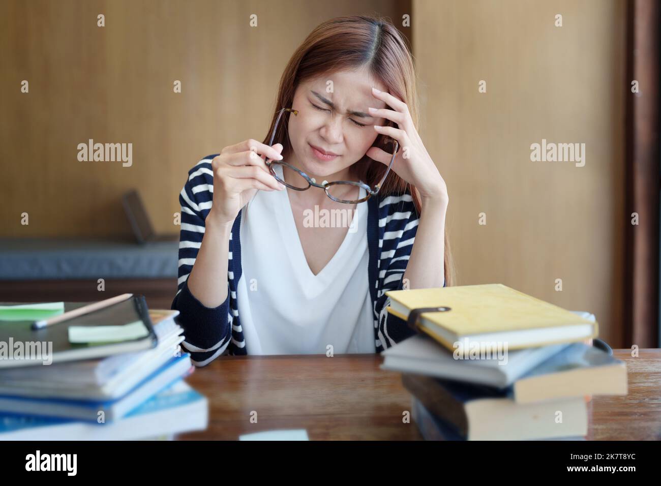 A portrait of an Asian teenage girl showing headaches and discouragement from studying in the ...
