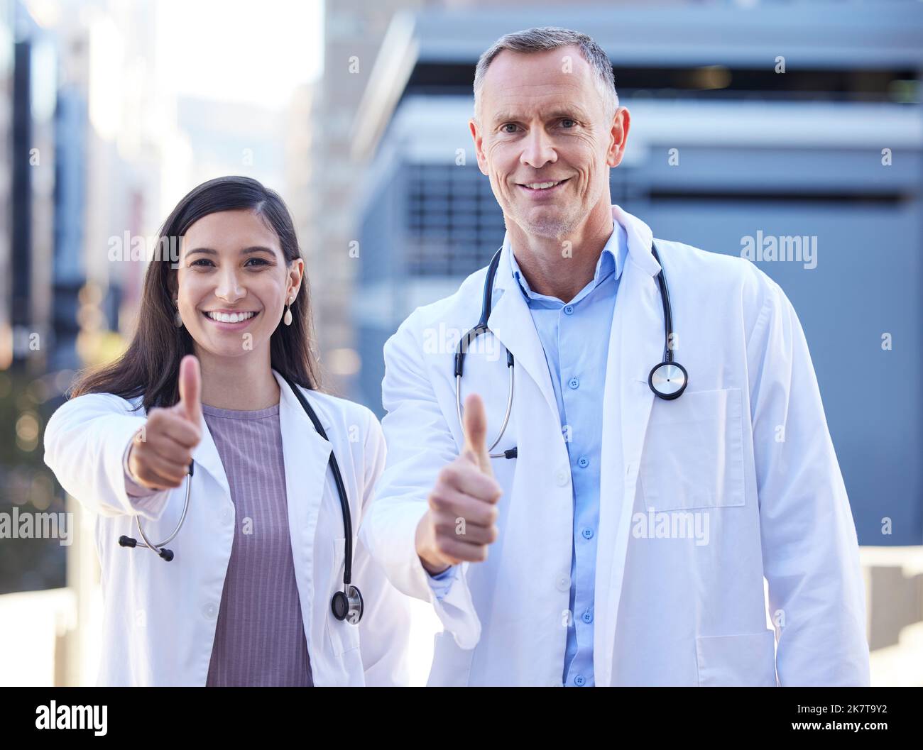 Humble and willing to fight. Portrait of two doctors showing thumbs up ...