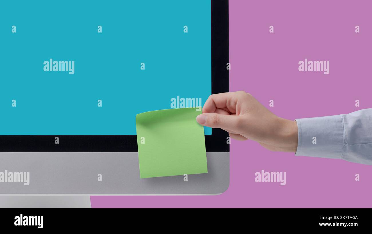 Woman sticking a note on the computer screen, ideas and planning ...