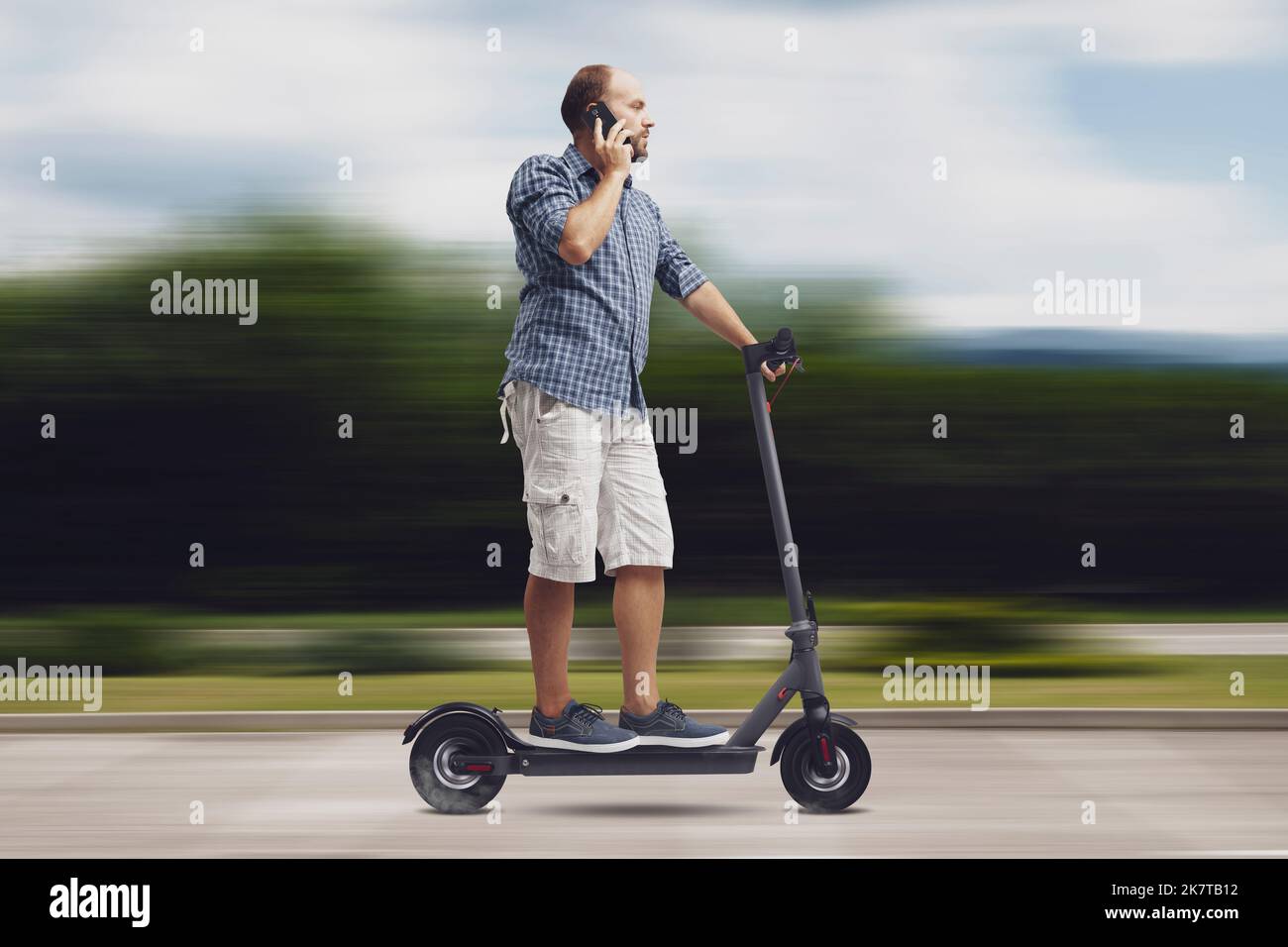 Man having a phone call with his smartphone and riding an electric ...