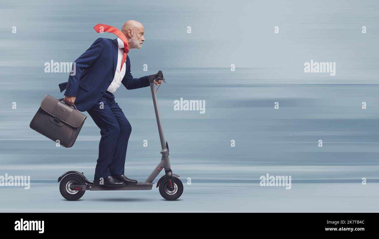Corporate businessman riding a fast eco-friendly electric scooter ...