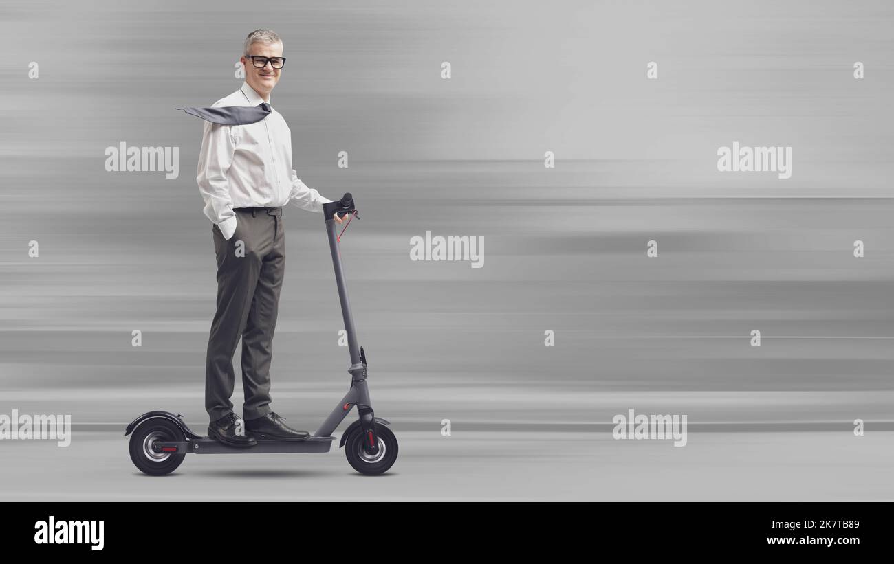 Corporate businessman riding a fast eco-friendly electric scooter ...