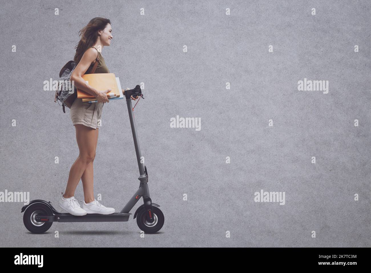 Happy female student riding an eco-friendly e-scooter, smart mobility ...