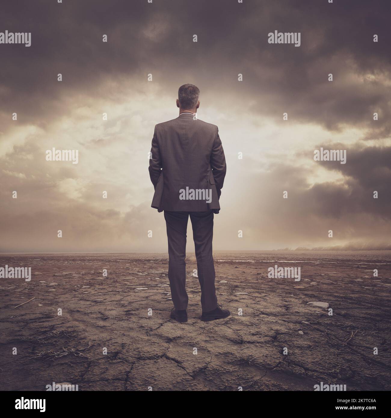 Businessman standing alone in a dry desert land, he is lost and ...