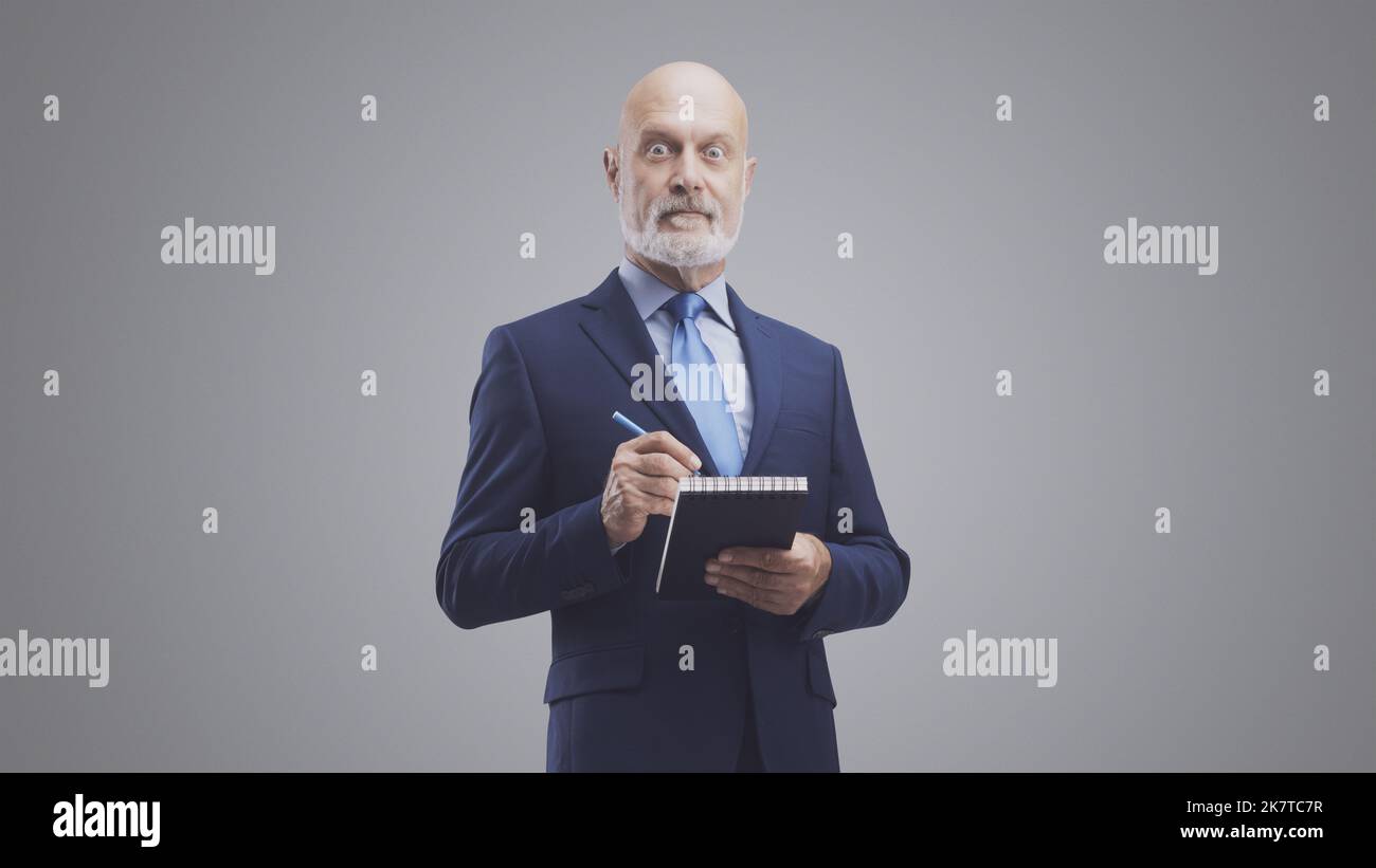 Business executive writing down notes and to do lists on a notebook ...