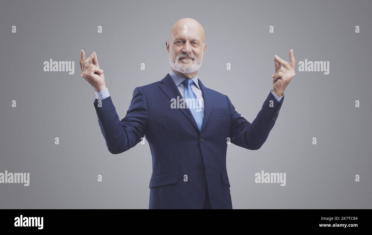 Smiling confident businessman snapping his fingers, isolated on gray ...