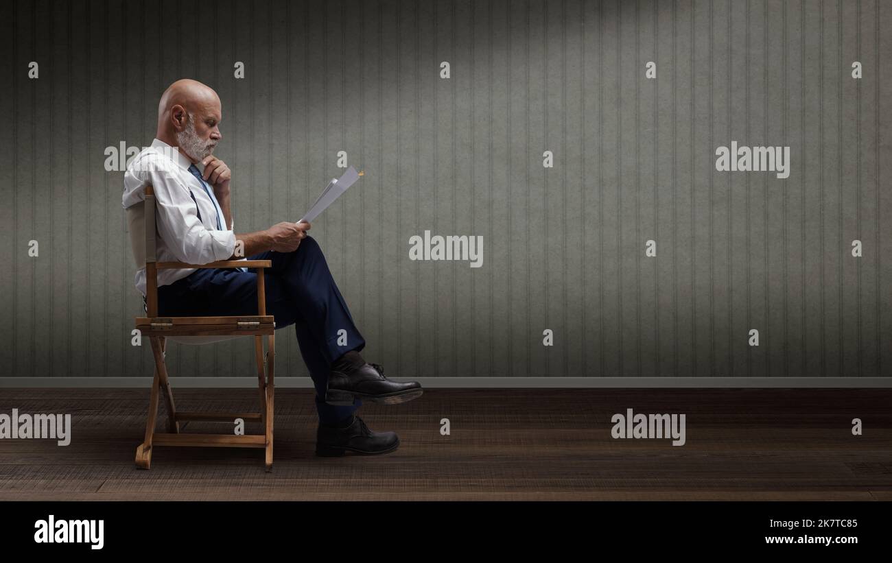 Professional film director sitting on the director's chair and reading ...