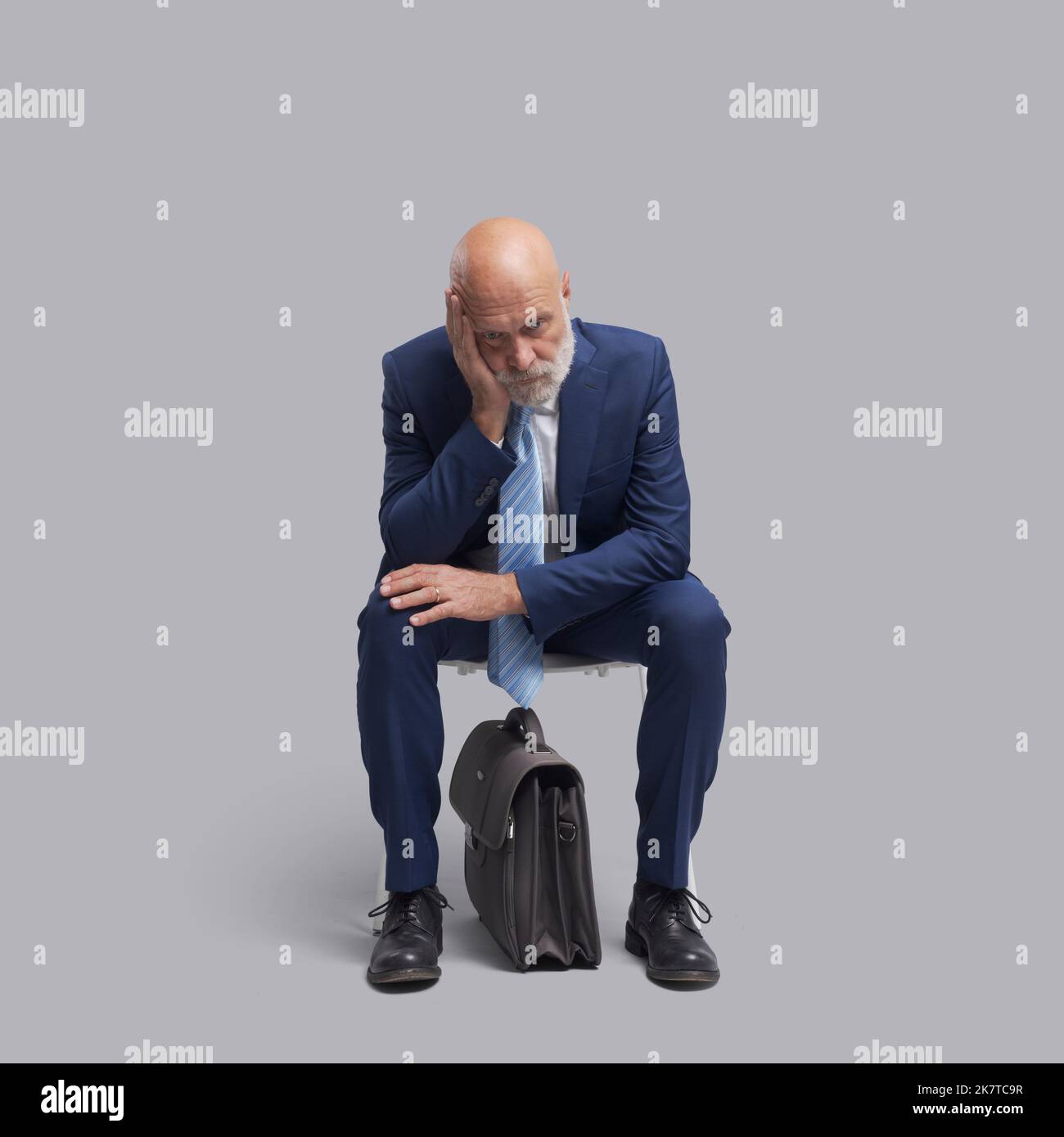 Bored frustrated corporate businessman sitting on a chair and waiting ...