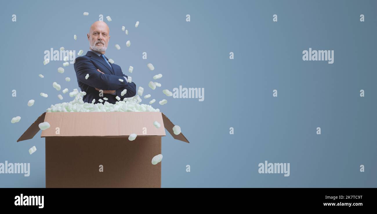 Confident businessman posing with arms crossed in a delivery box, new ...