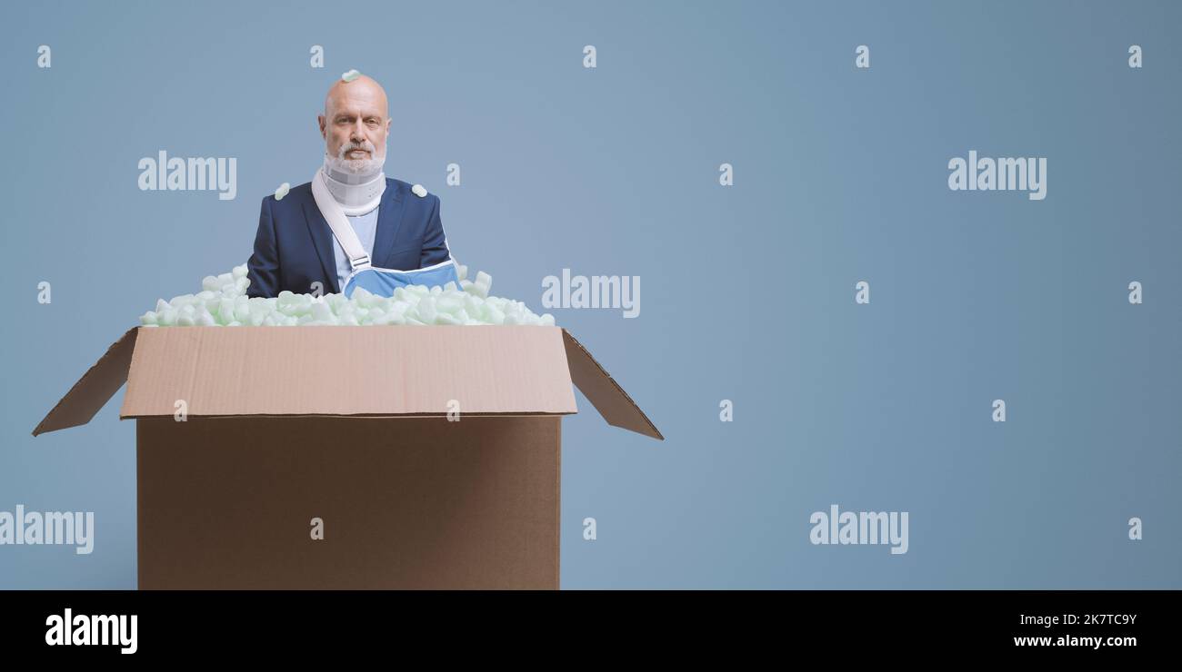 Sad injured man with cervical collar and broken arm in a delivery box ...