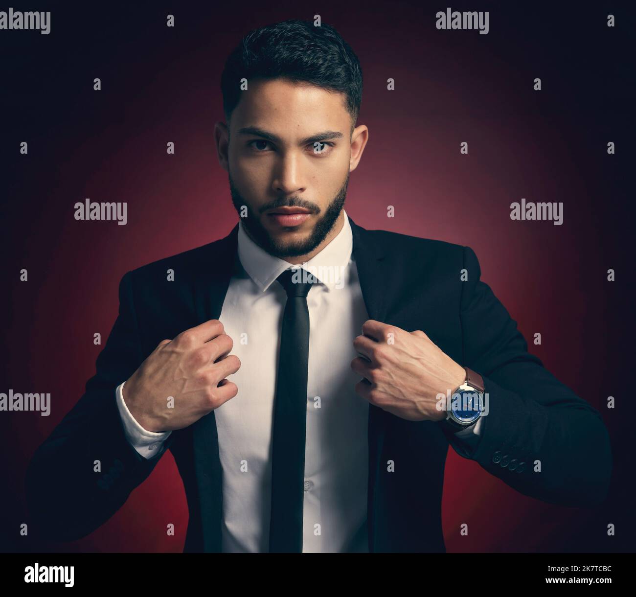Turn up the charm. Studio shot of a young man posing against a red ...