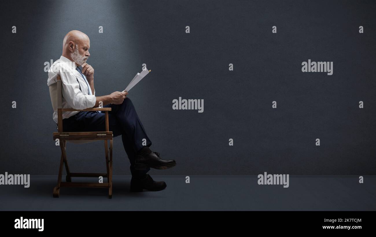 Professional film director sitting on the director's chair and reading ...