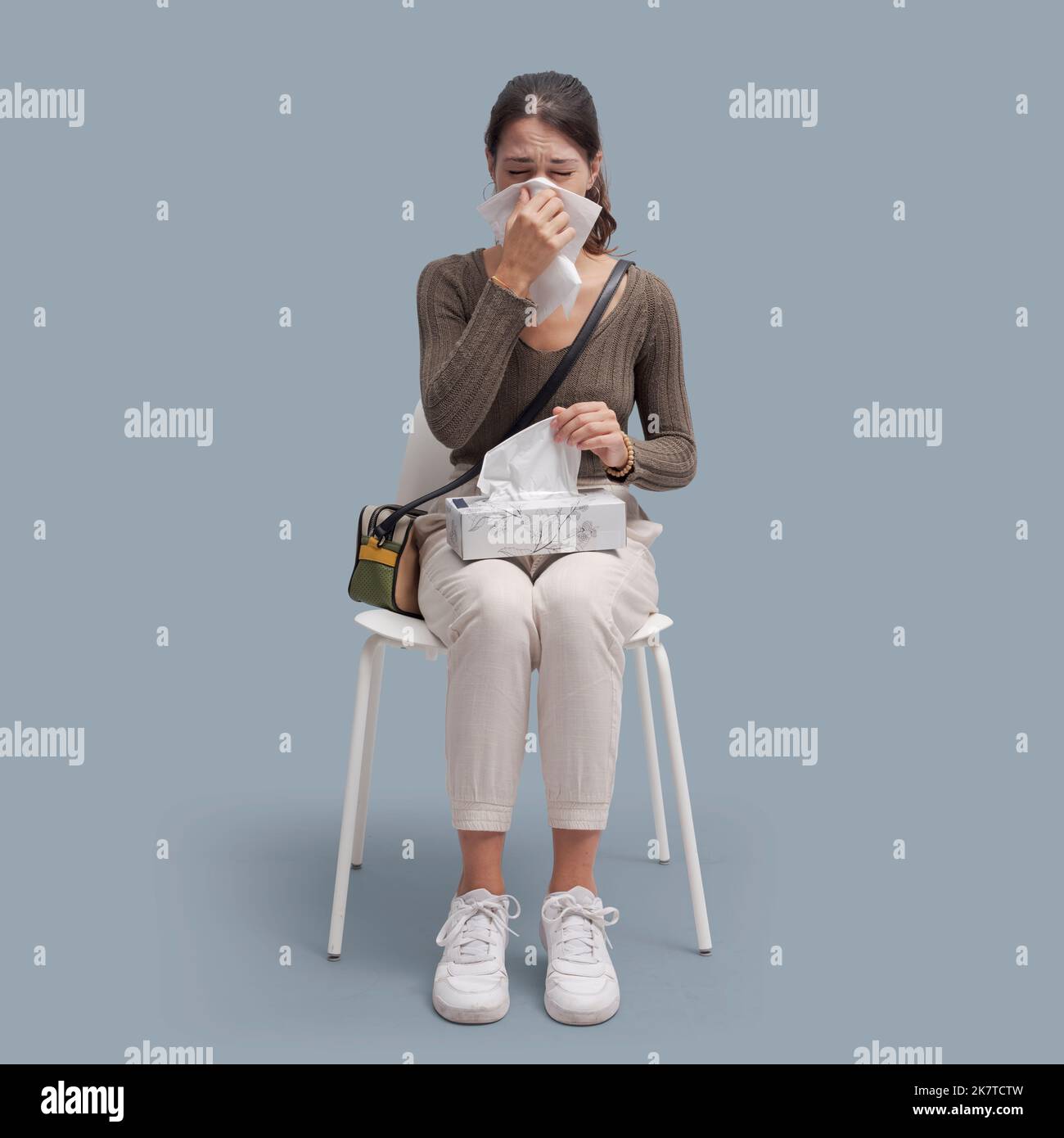 Patient sitting on a chair and waiting, she has cold and flu and she is ...