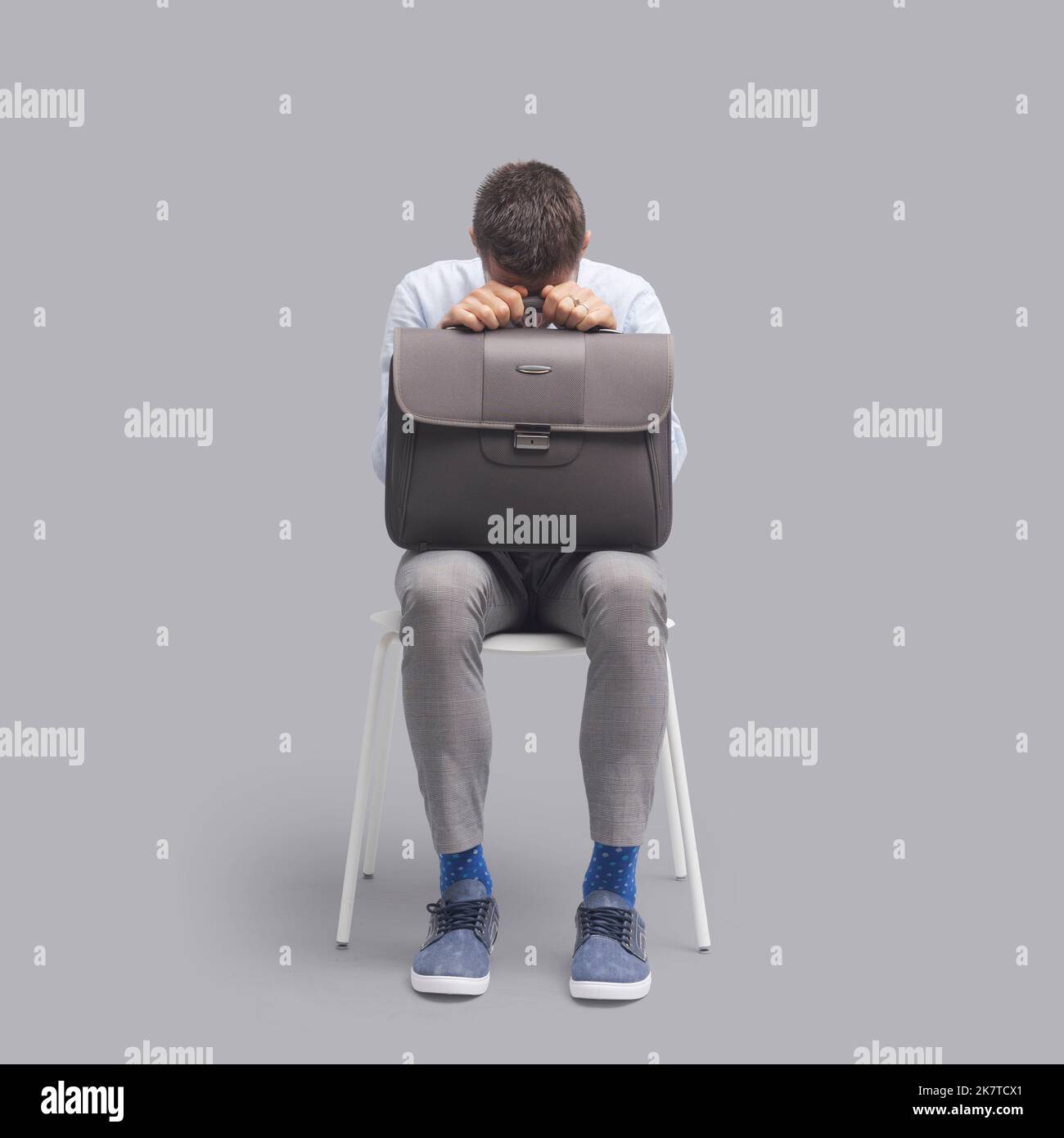 Bored man sitting on a chair and waiting for a meeting or a job ...