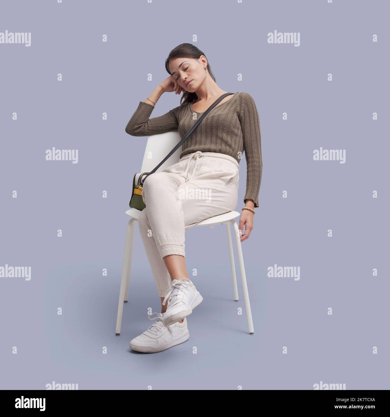 Young cute teenager sitting on a chair and sleeping, she is tired and ...