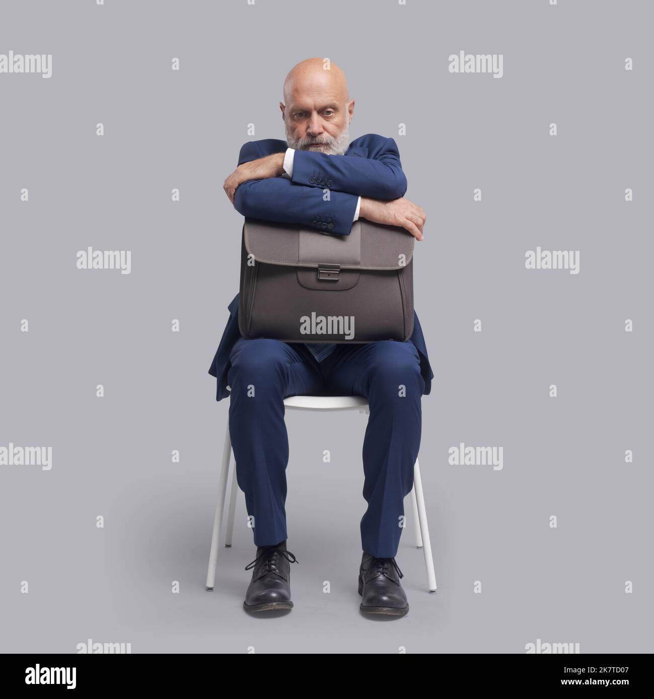 Bored frustrated corporate businessman sitting on a chair and waiting ...