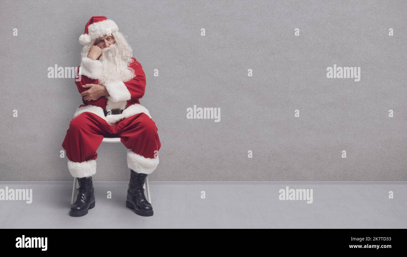 Bored Santa Claus sitting on a chair and waiting for a job interview ...