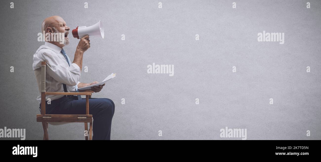 Confident professional film director sitting on the director's chair ...