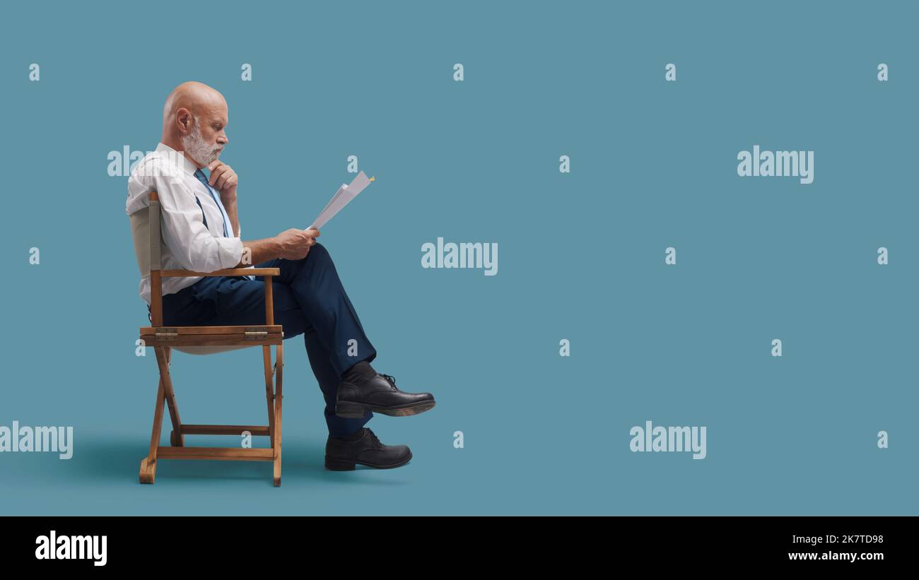 Professional film director sitting on the director's chair and reading ...