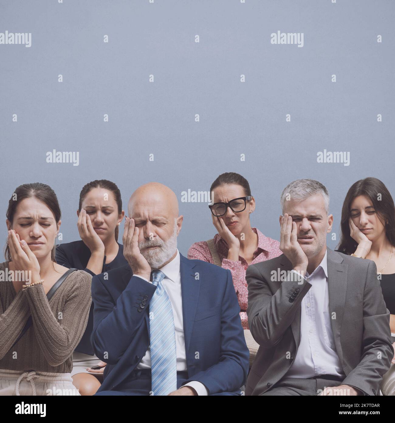 Diverse people sitting in a waiting room and touching their cheeks ...