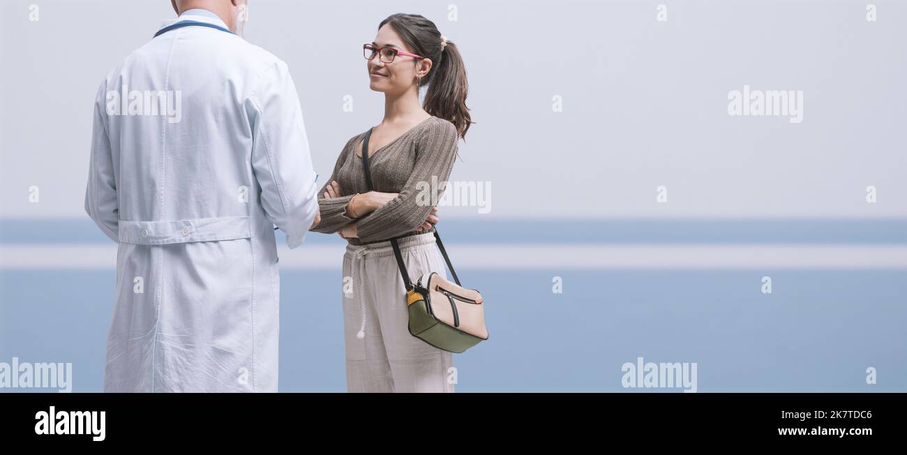 Doctor meeting a young female patient in the hospital aisle, they are ...