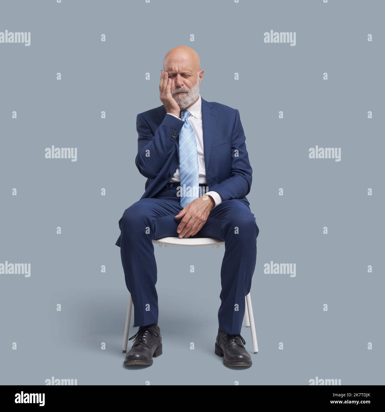 Man sitting on a chair and touching his cheek, he is having a bad ...