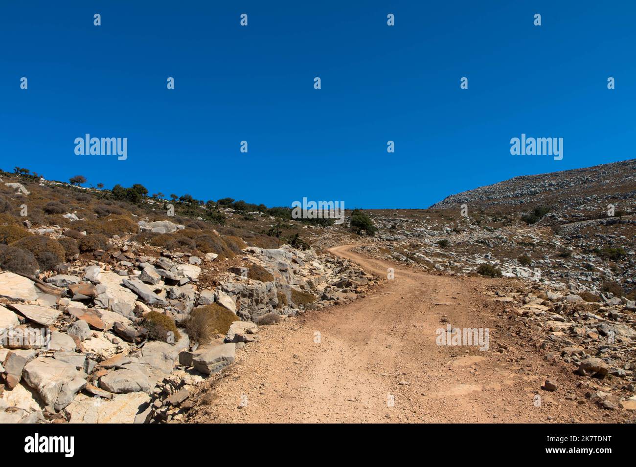 Gravel road to the top of Attavyros mountain. Arid landscape and blue ...