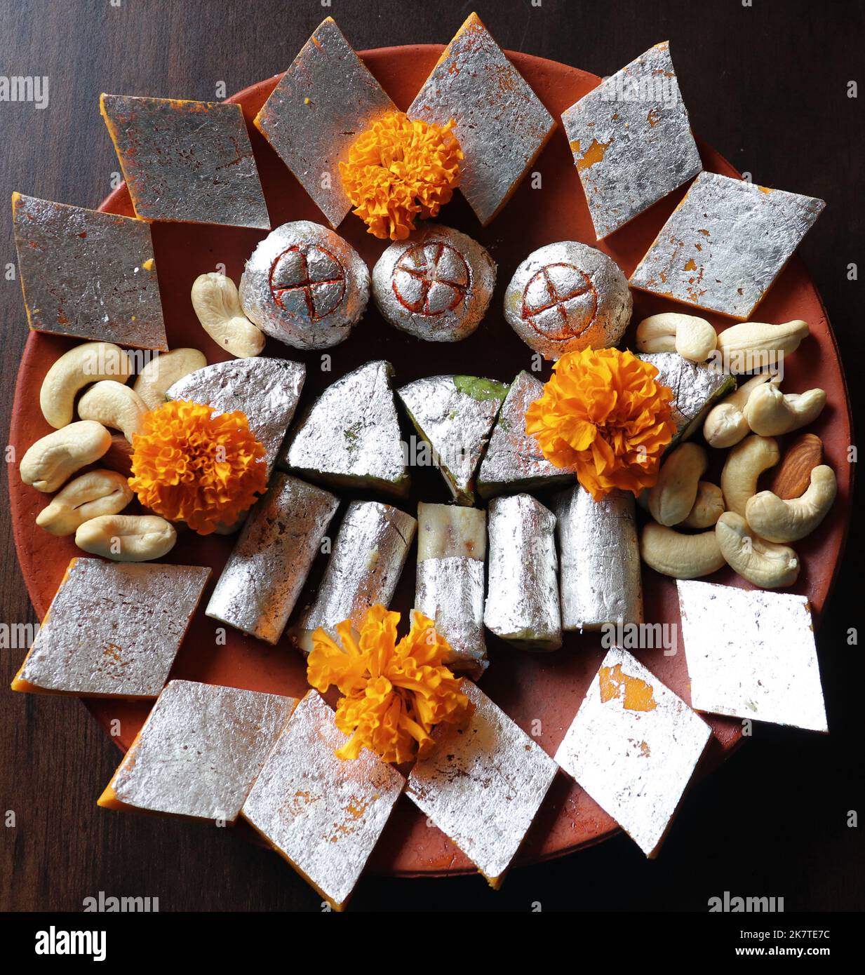 Assorted Indian sweets/dry fruits/marigold flower in a terracotta/clay ...